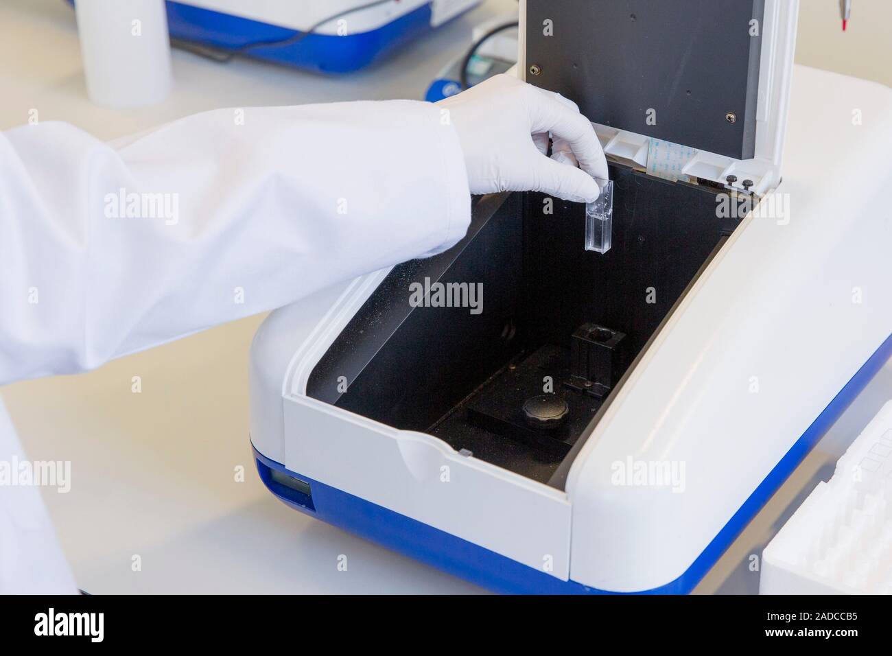 Scientist loading cuvette sample into UV spectrometer for analysis ...