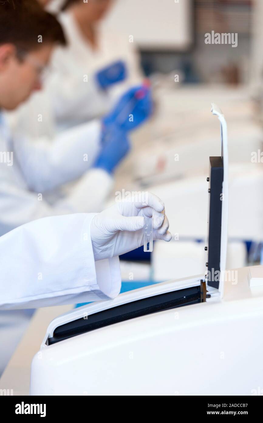 Chemistry student loading cuvette sample into UV spectrometer for ...