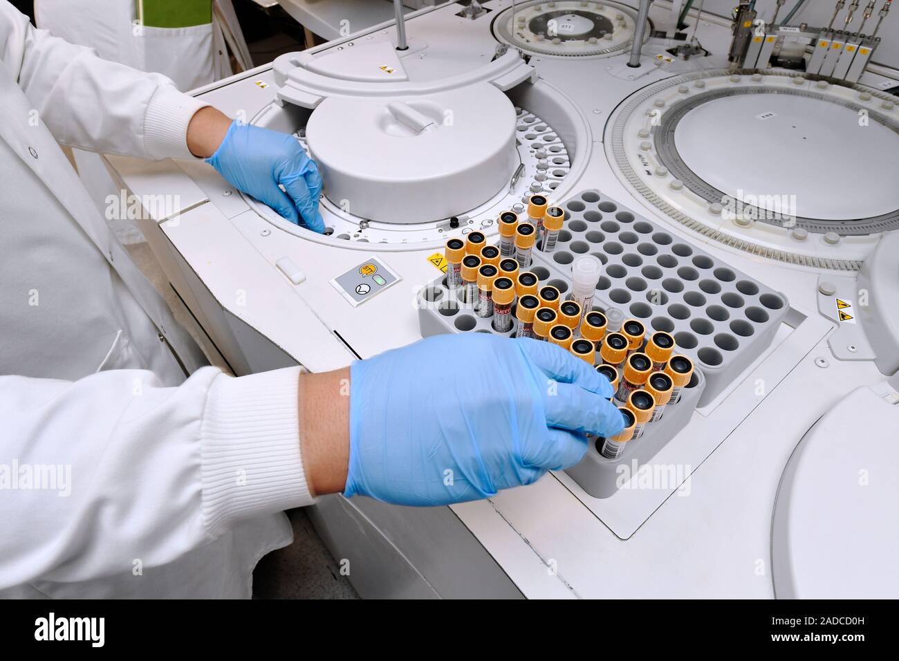 Automated biochemistry analyser. Laboratory technician placing blood ...