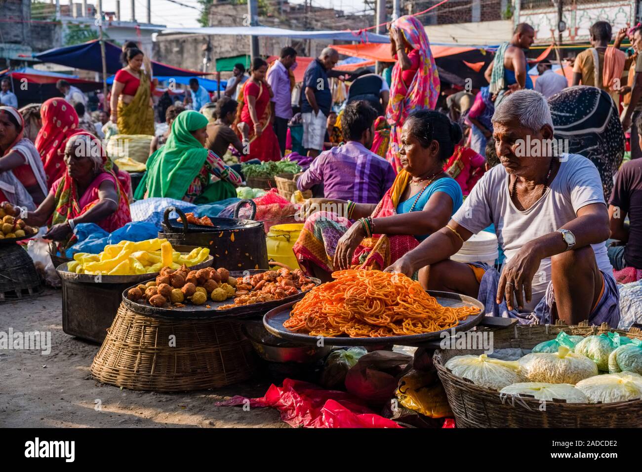 A man and a woman are offering snacks at the weekly vegetable market ...