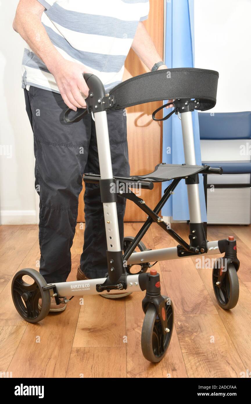 A man with impaired mobility using a mobility frame with wheels and ...