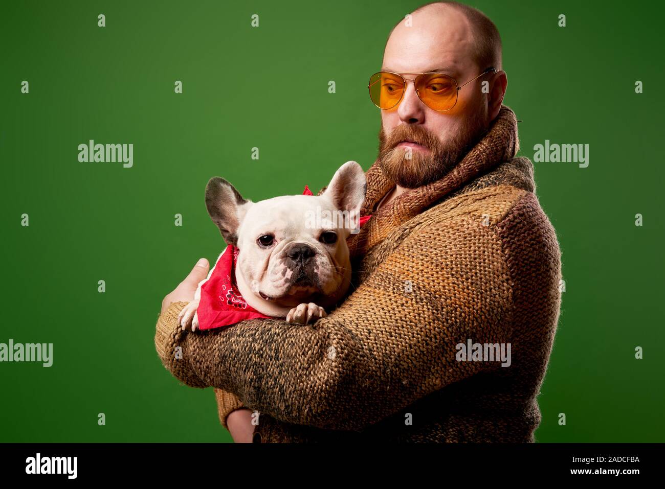 Man in glasses with french bulldog in his arms on empty green ...