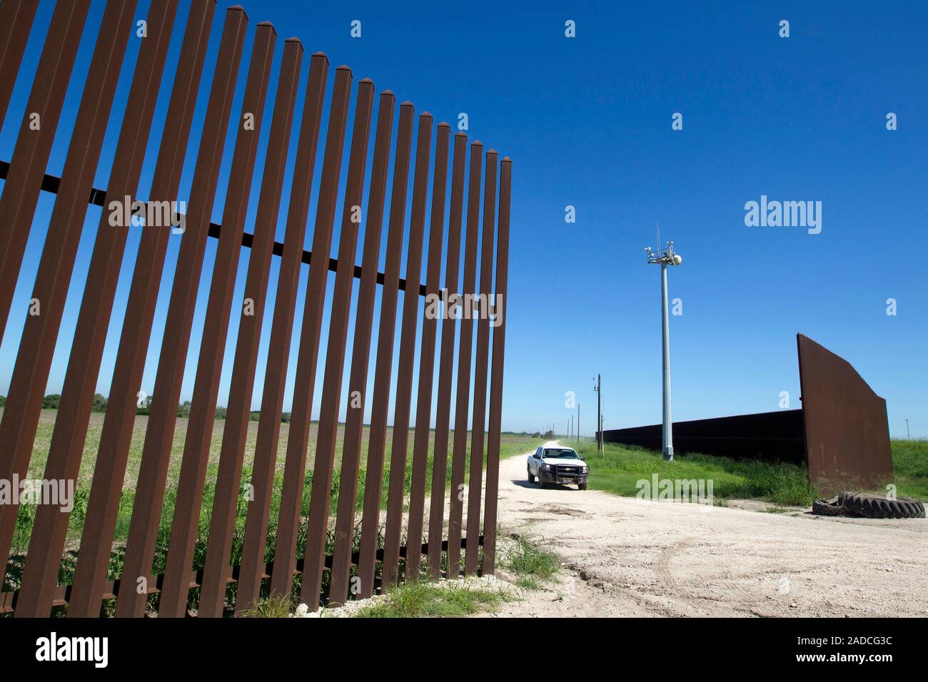 US-Mexico border fence. Car on a road crossing the fence line that runs ...