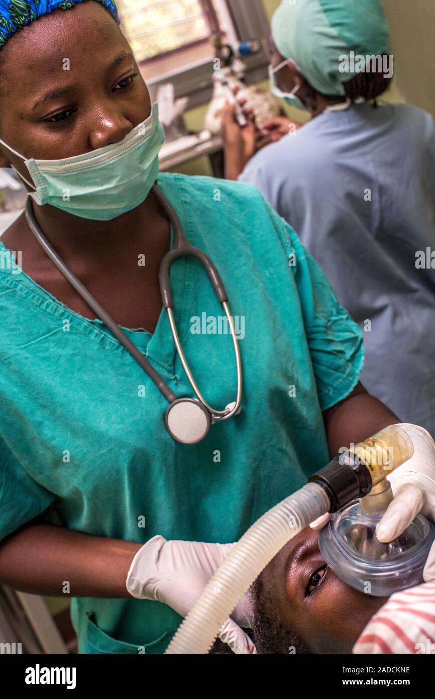 Caesarean section preparation. Anaesthetist delivering drugs to a woman ...