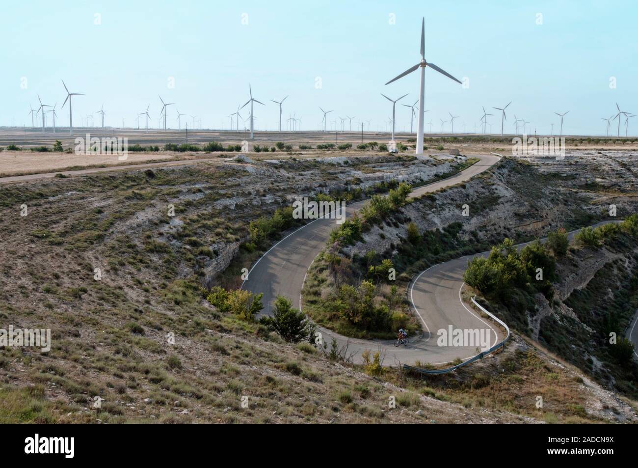 Wind turbines by a winding road, forming part of a wind farm. Wind ...