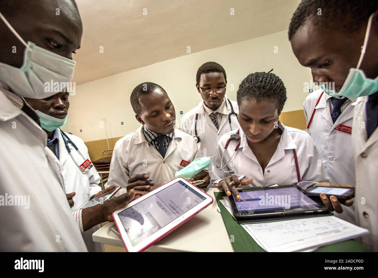 Medical students and doctors discussing cases and using tablet ...