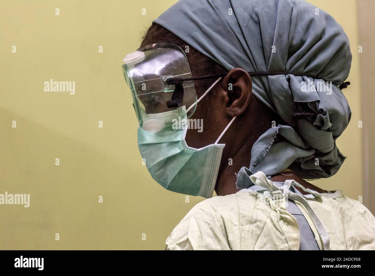 Surgical nurse wearing a face-mask and protective goggles. Photographed ...
