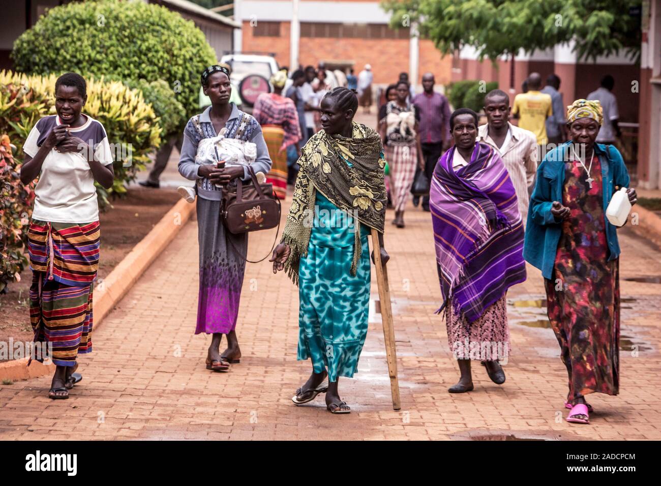 Ugandan women walking along a street, with the woman at centre using a ...