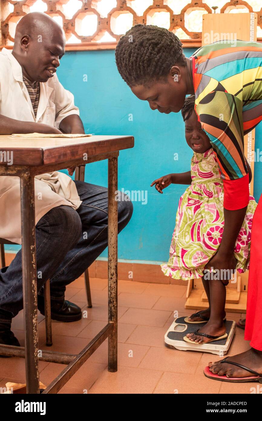 Weighing a child. Doctor and mother using a set of scales to weigh a ...
