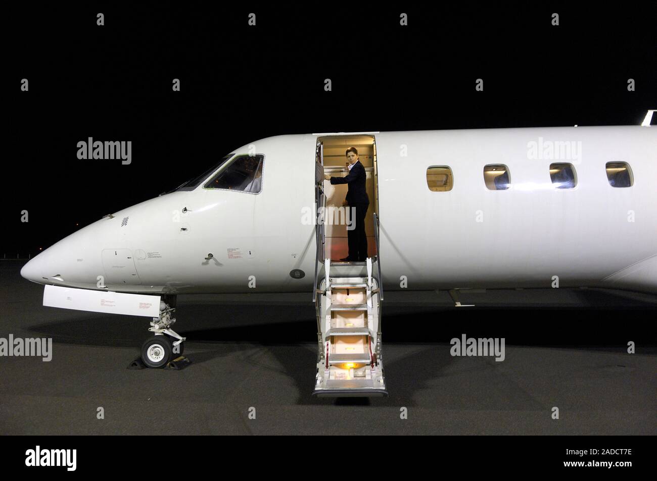 Nose of Embraer ERJ-135LR parked with stewardess standing in the open ...