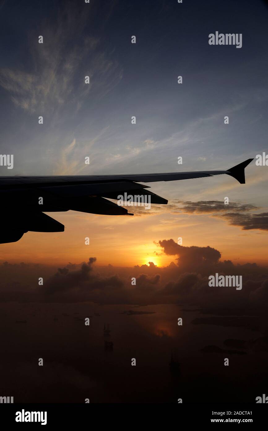 Sunrise over the Straits of Singapore, with the wing and winglet of an ...