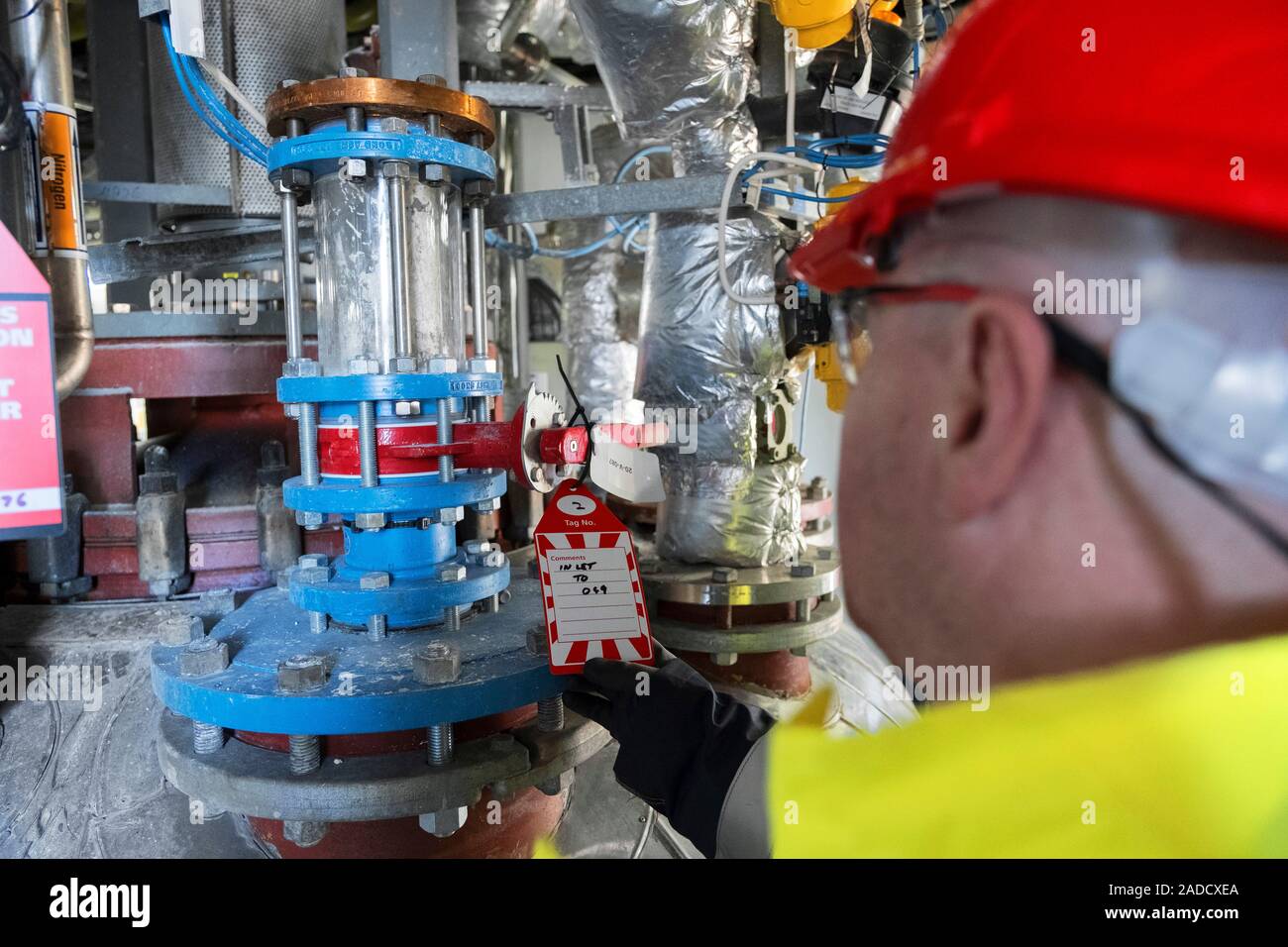 CalaChem chemical factory. Worker looking at a process isolation tag at ...