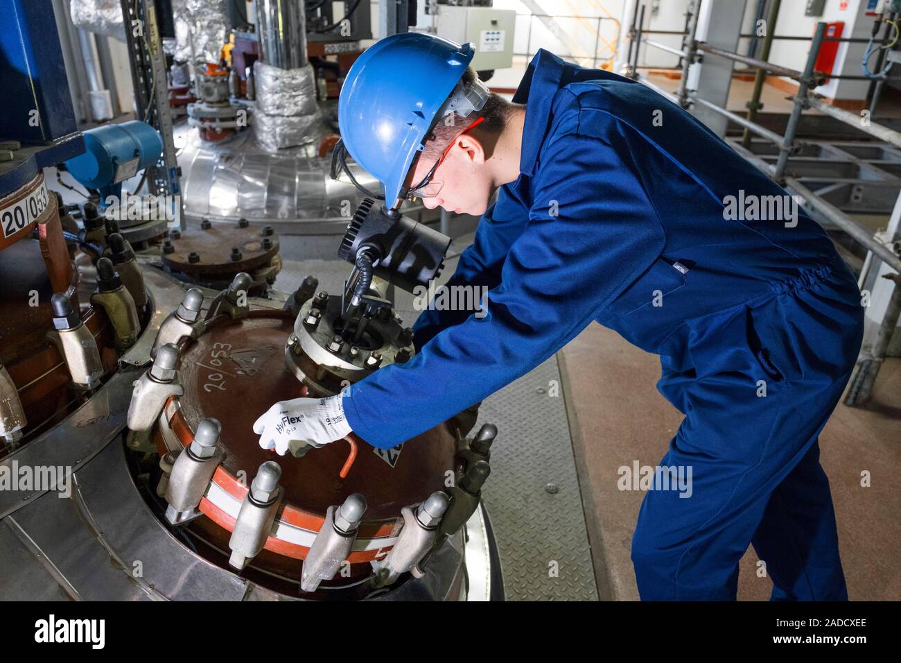CalaChem chemical factory. Worker looking through a glass lined viewing ...