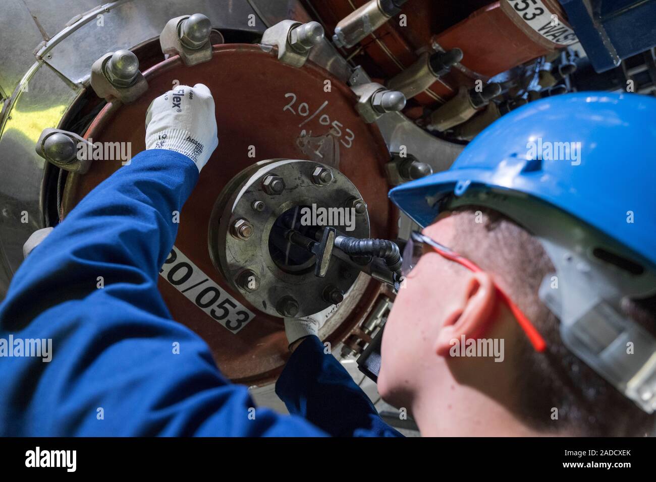 CalaChem chemical factory. Worker looking through a glass lined viewing ...