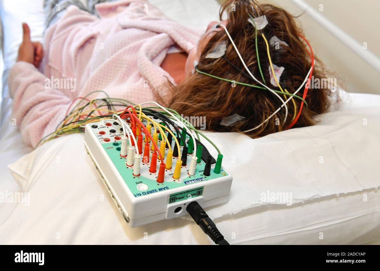 Electroencephalography. Woman with electrodes attached to her head as ...