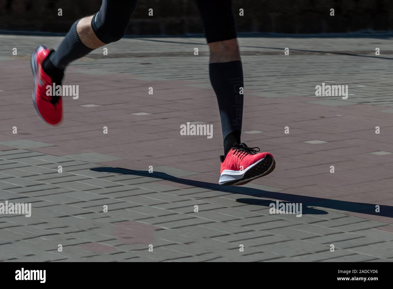 Running legs on sunny pavement Stock Photo - Alamy