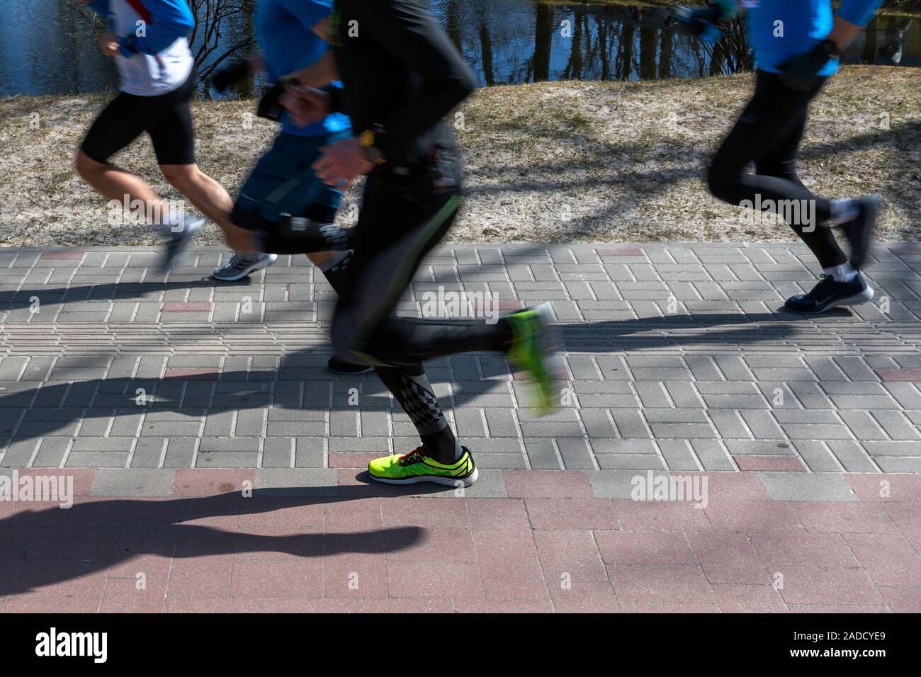 Running legs on sunny pavement Stock Photo - Alamy