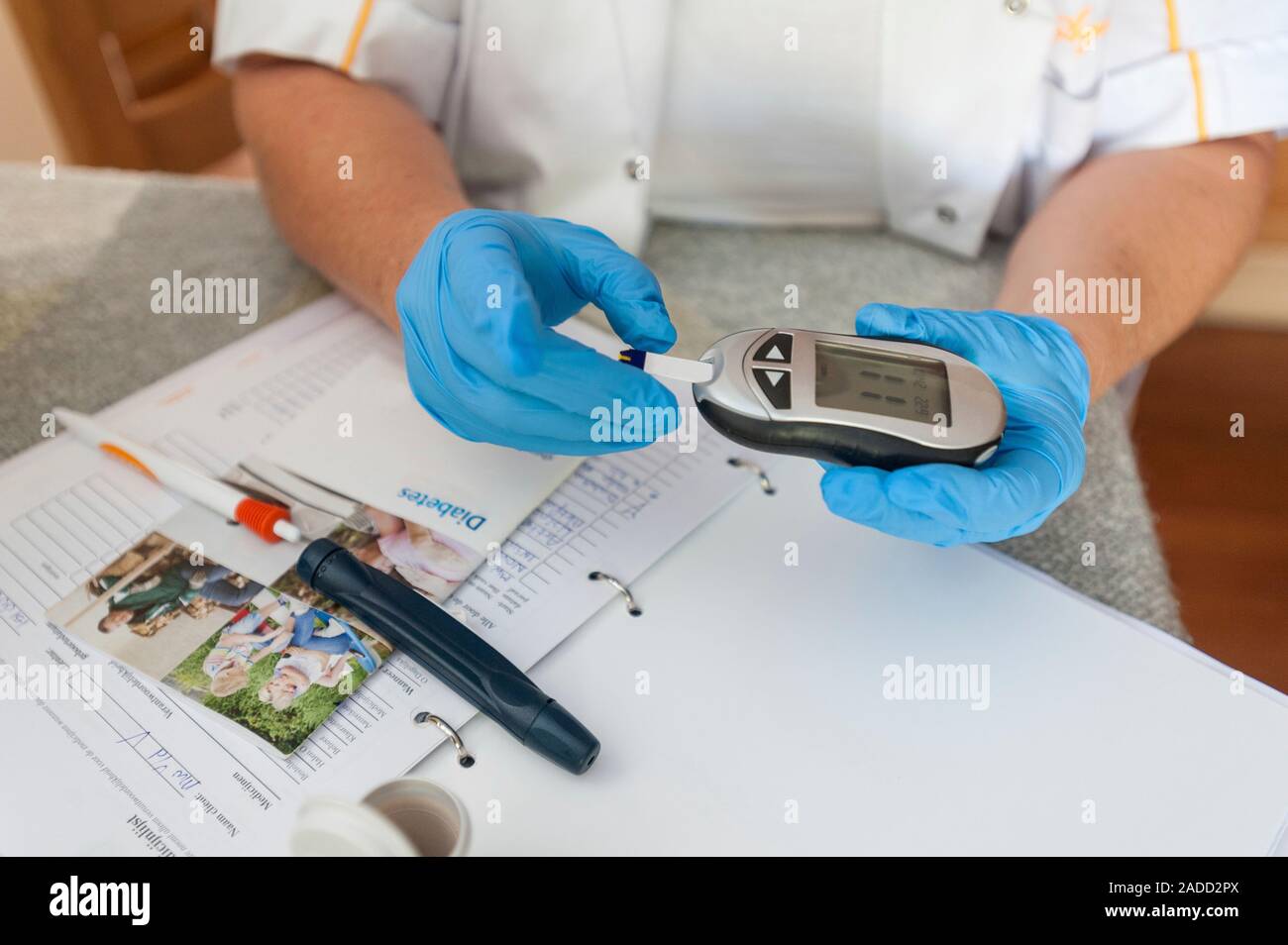 Diabetes blood sugar test. Hands of a nurse using a testing device on ...