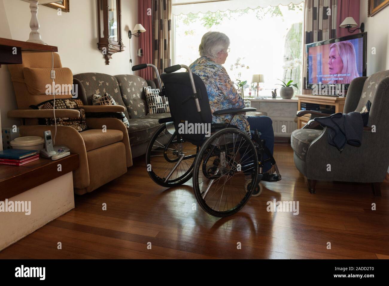 Elderly woman watching television. 76-year-old woman in a wheelchair ...