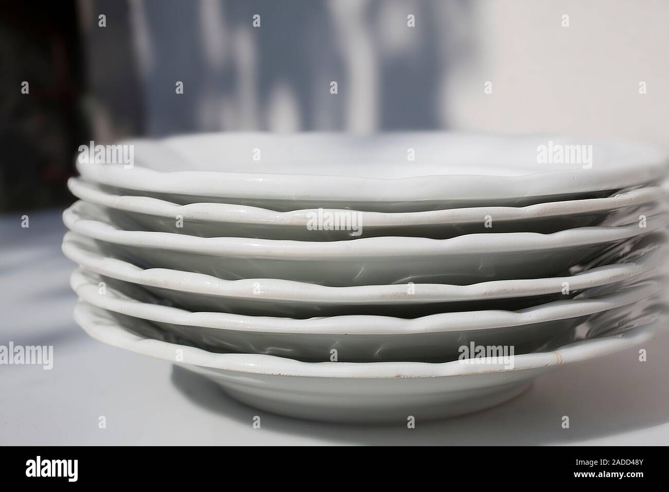 plates stacked on a pile on the edge of a table Stock Photo - Alamy
