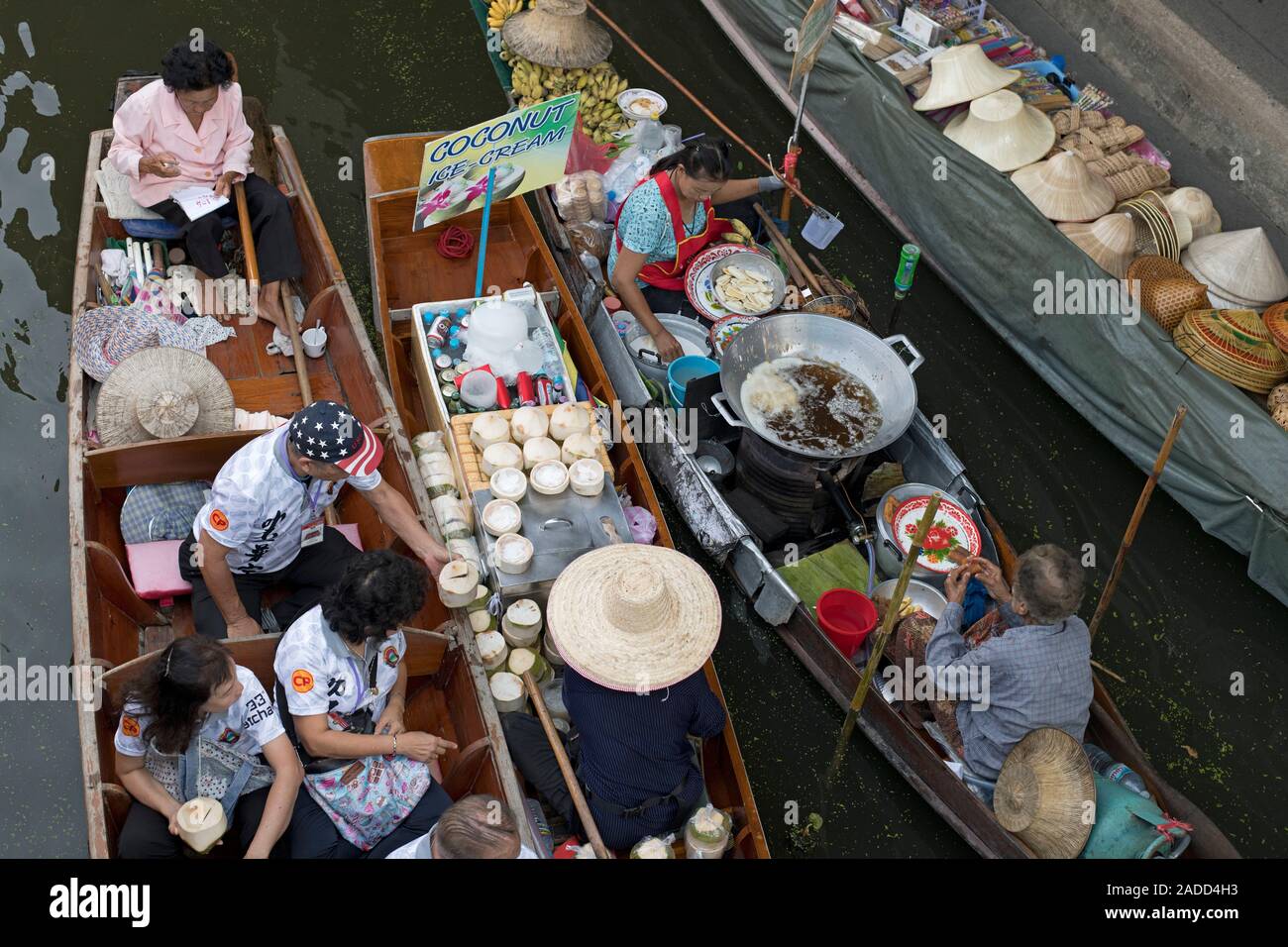 A Thai woman vendor selling ice-cream to tourists from her rowing boat ...