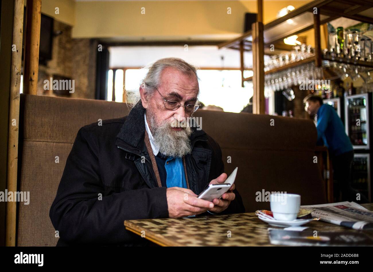 Mobile phone use. Older man using a smartphone in a pub Stock Photo - Alamy
