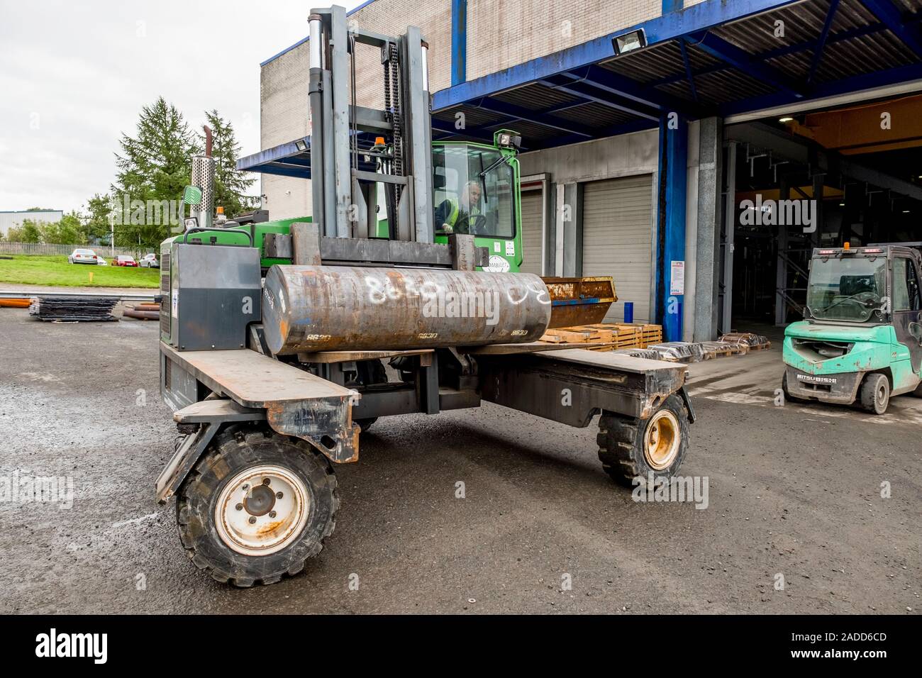 Metalworks. Worker using a forklift to load large forged steel bars for ...