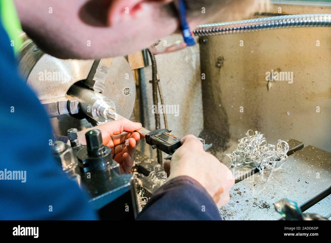 Metalworks. Worker operating a CNC (computer numerical control) lathe ...