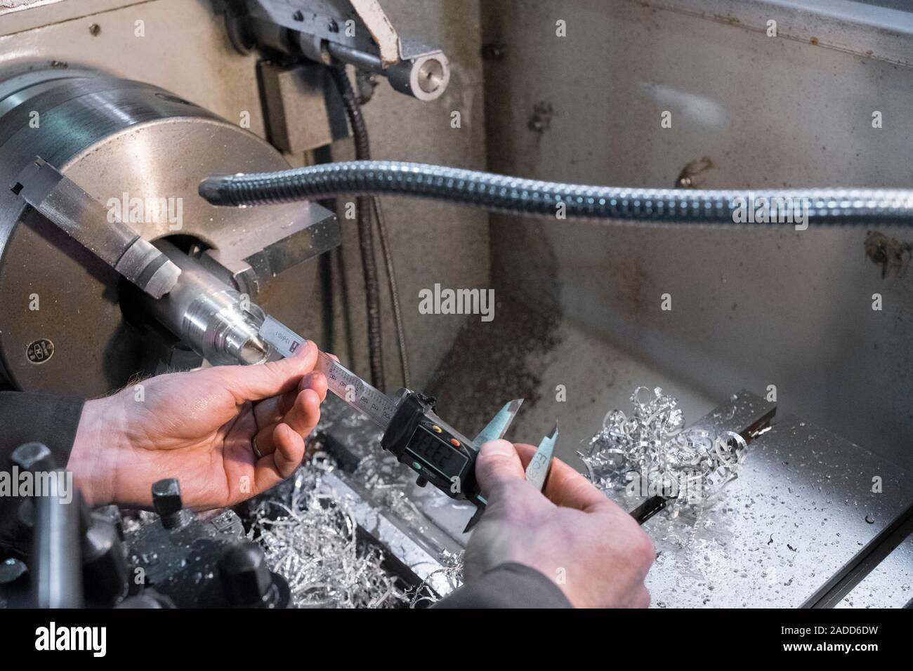 Metalworks. Worker operating a CNC (computer numerical control) lathe ...