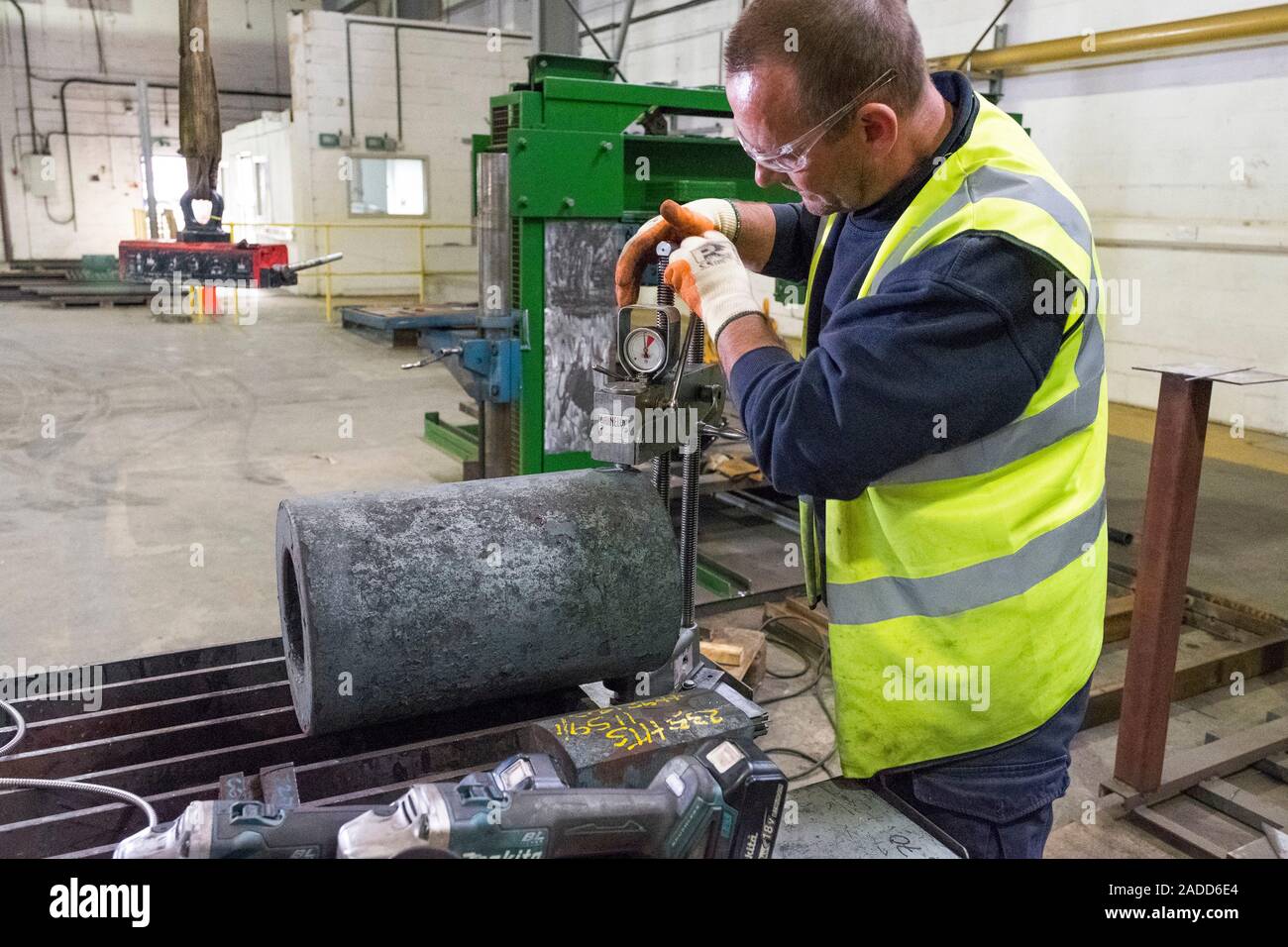 Metalworks. Worker mechanical testing a finished steel tube section at ...