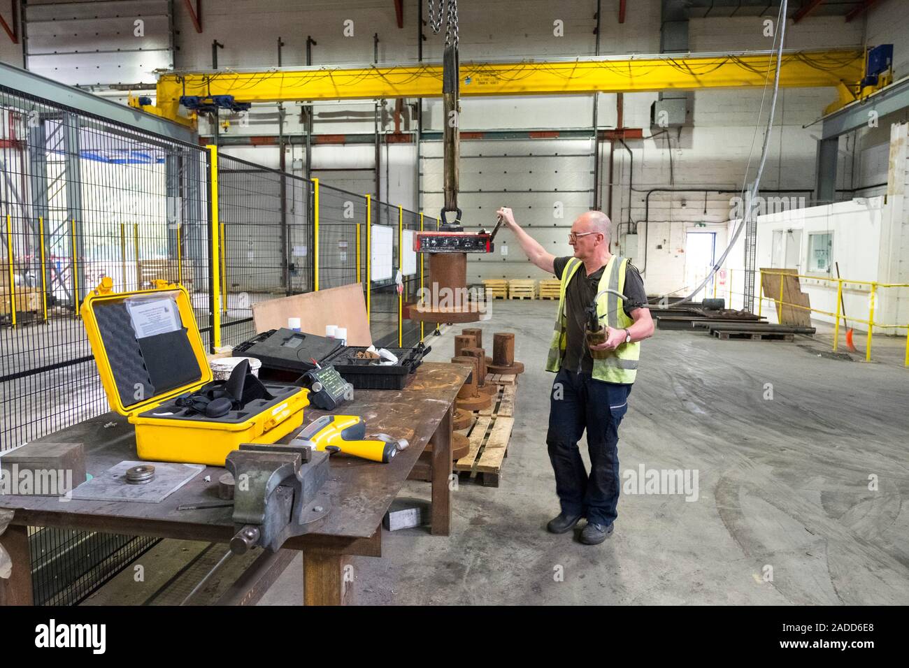 Metalworks. Worker with a magnetic crane used to move smaller steel ...
