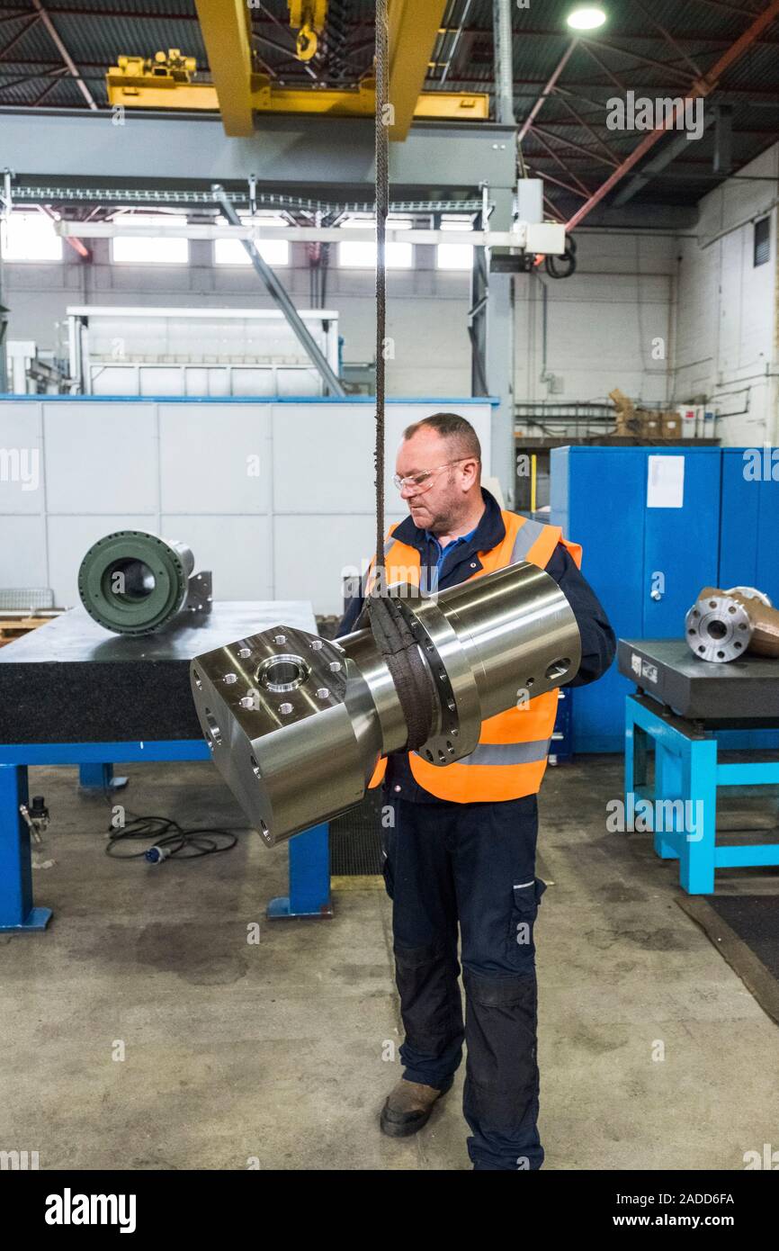 Metalworks. Worker with precision engineered steel parts made at a ...