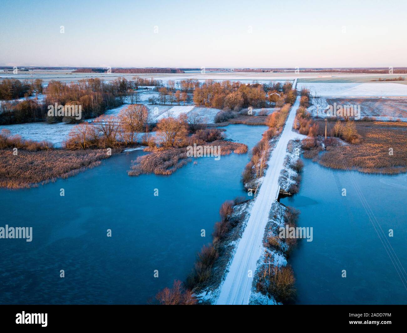 Aerial view of lake and snow covered bridge over it during nice sunrise ...