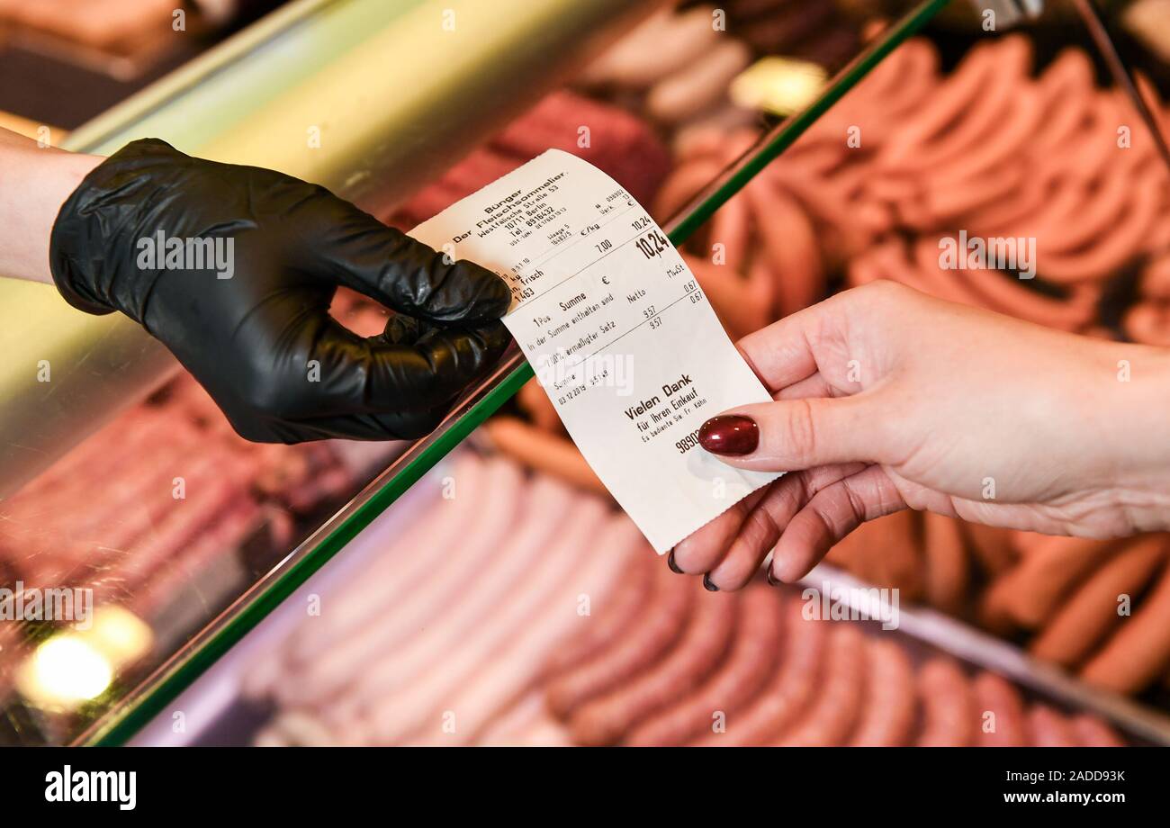 03 December 2019, Berlin: A butcher's shop assistant gives the receipt ...