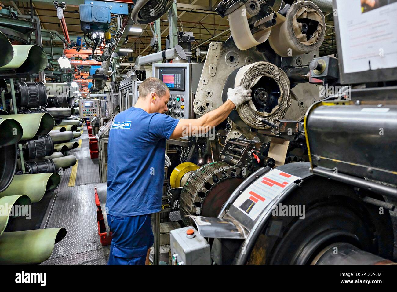 Tyre factory. Worker operating a tyre building machine at a factory ...