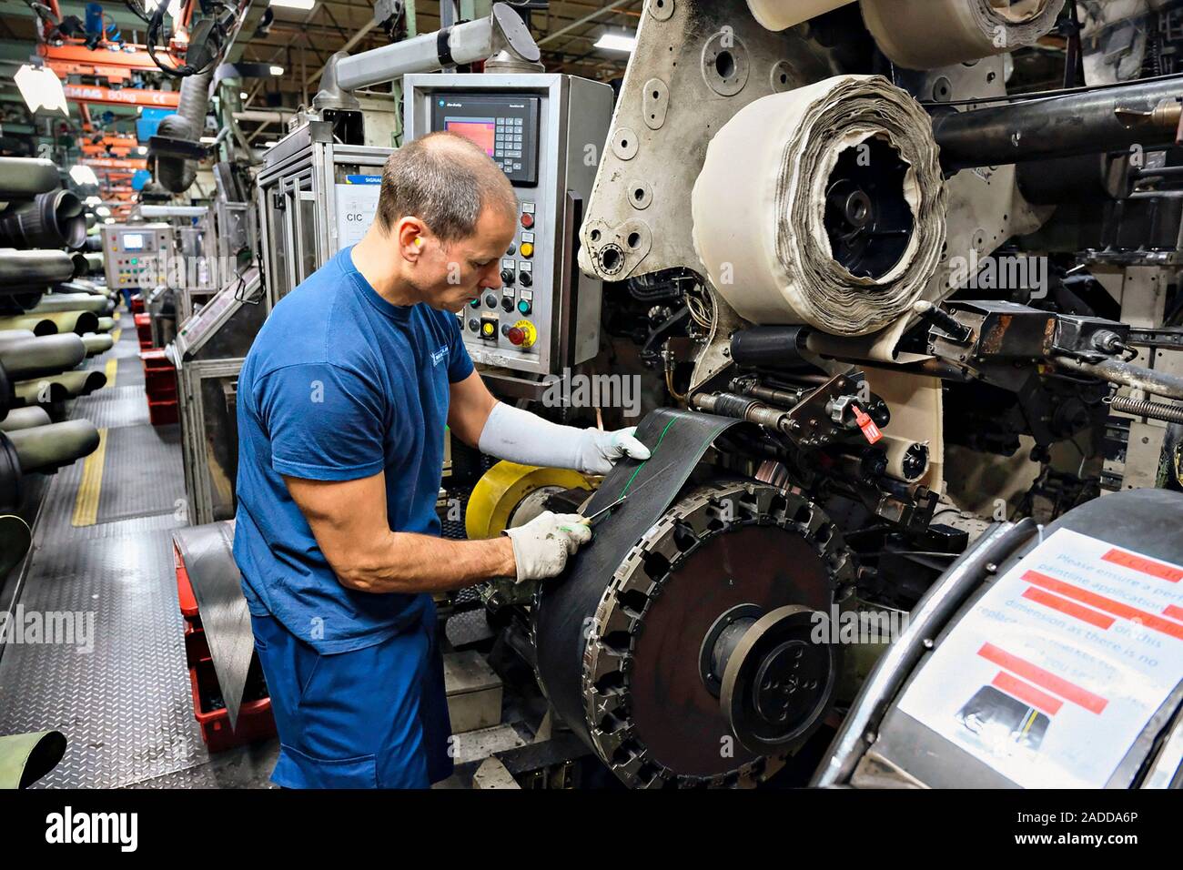 Tyre factory. Worker operating a tyre building machine at a factory ...