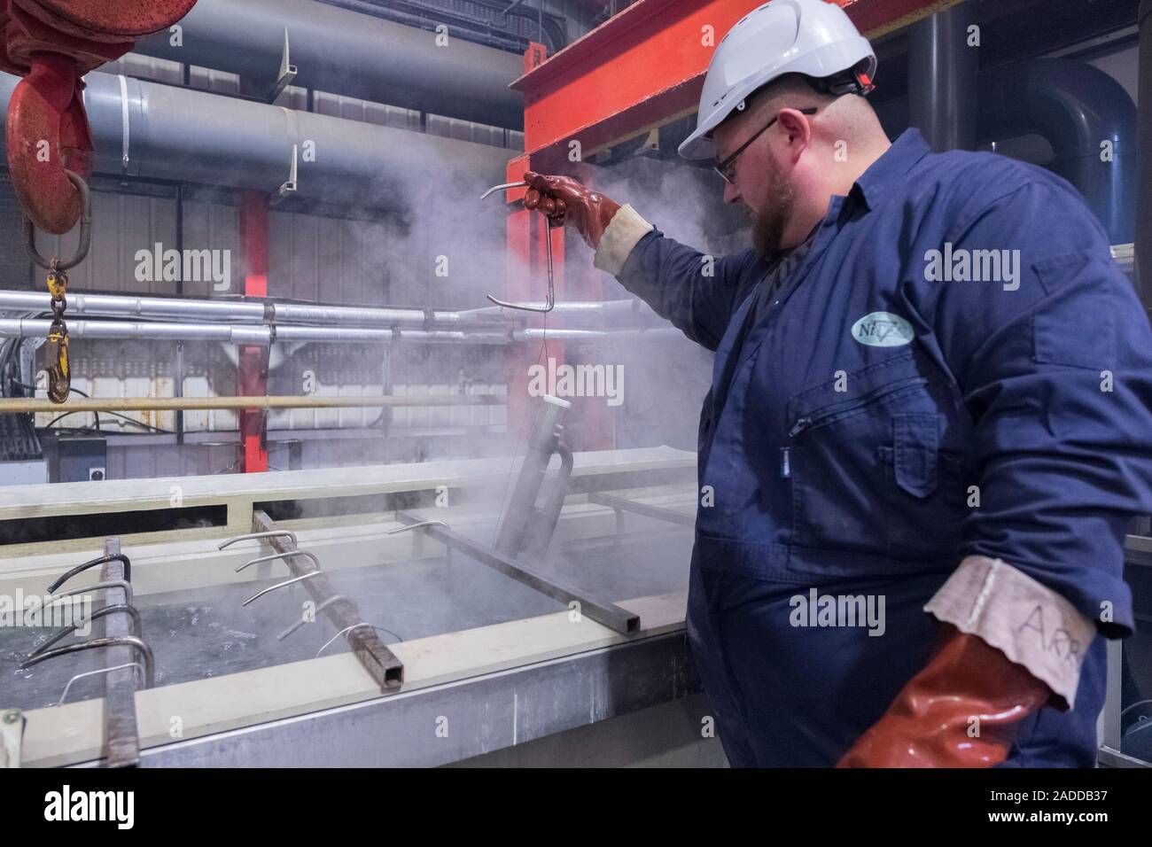Electroless nickel plating factory. Worker checking products in a ...