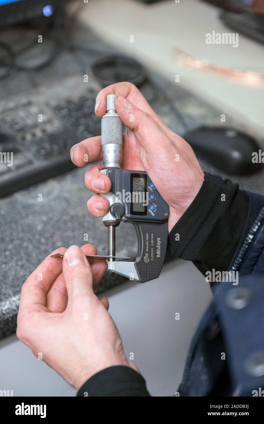 Electroless nickel plating factory. Worker checking the thickness of ...