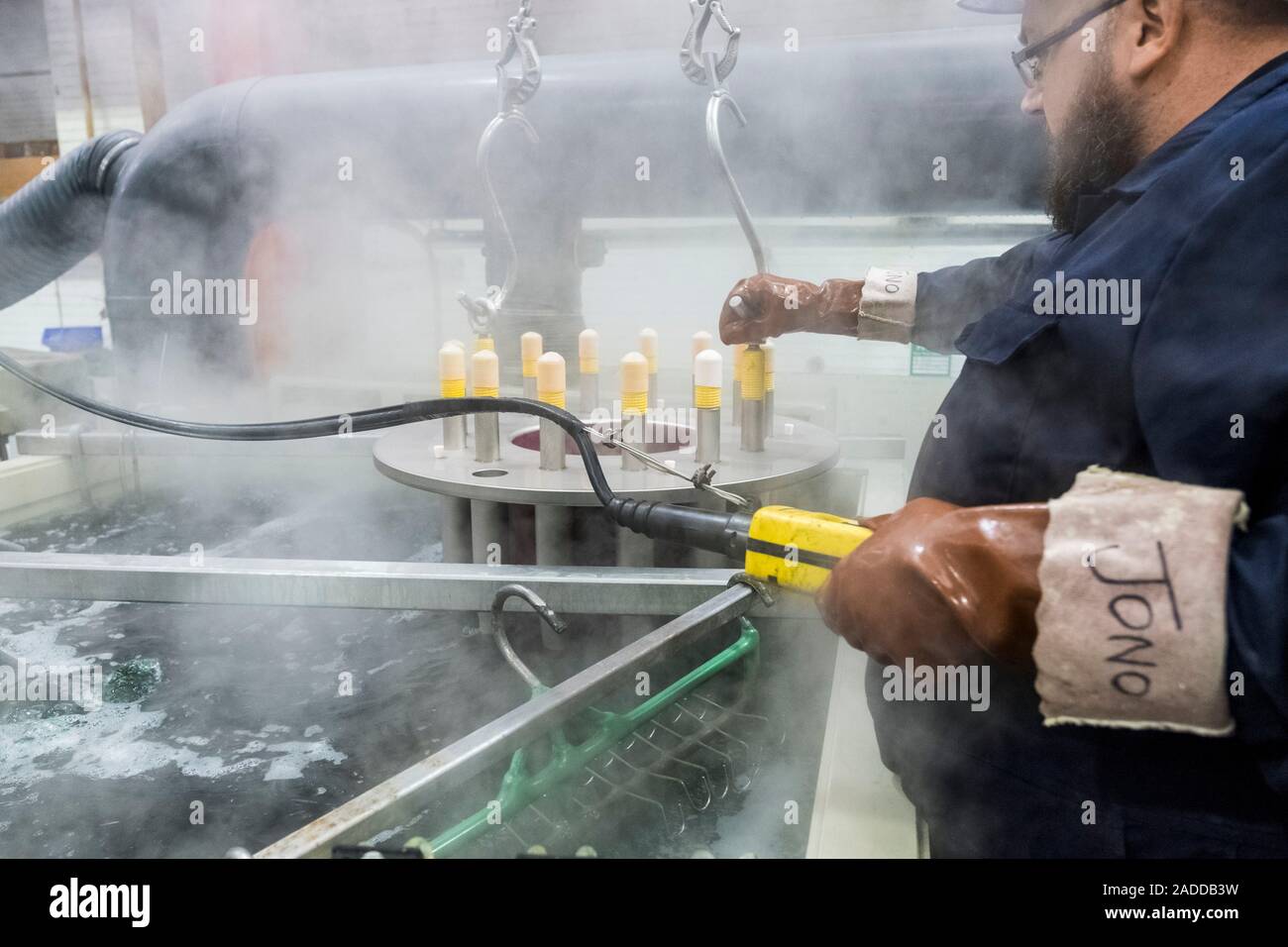 Electroless nickel plating factory. Worker placing products in a ...