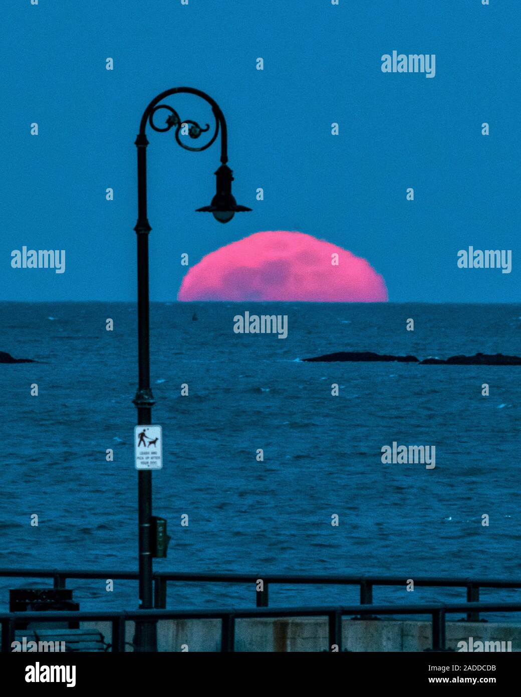 Full moon rising over the Atlantic Ocean. It is distorted and reddened ...