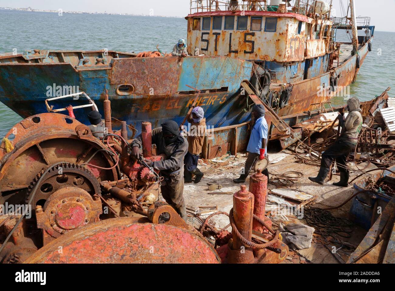 Boat scrapyard. Workers dismantling decaying and rusting fishing boats ...
