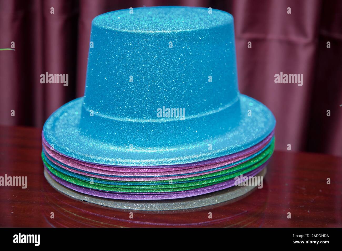 Blue metallic party hat . Blue magician performer hat on a isolated red ...