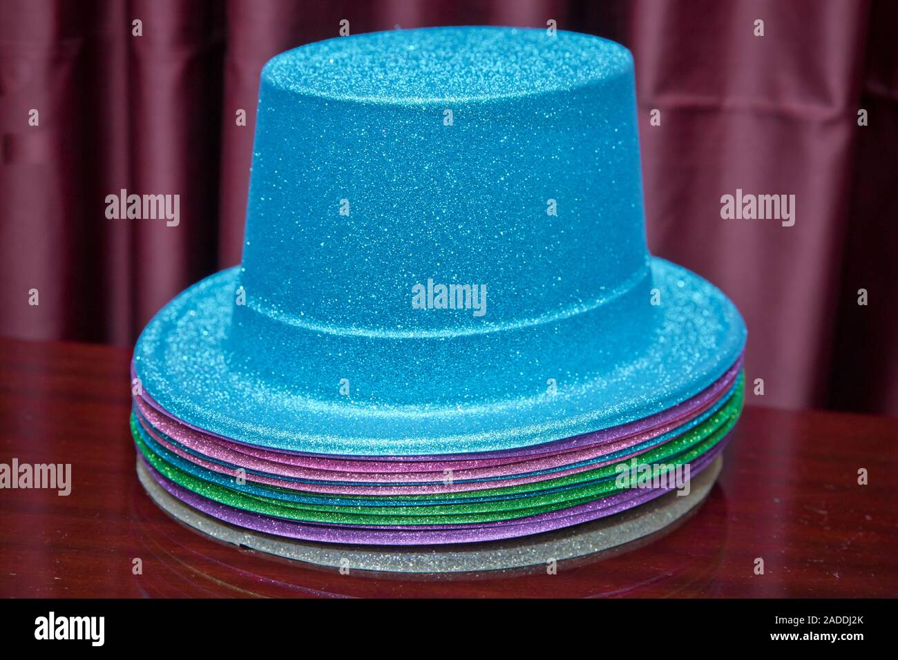 Blue metallic party hat . Blue magician performer hat on a isolated red ...