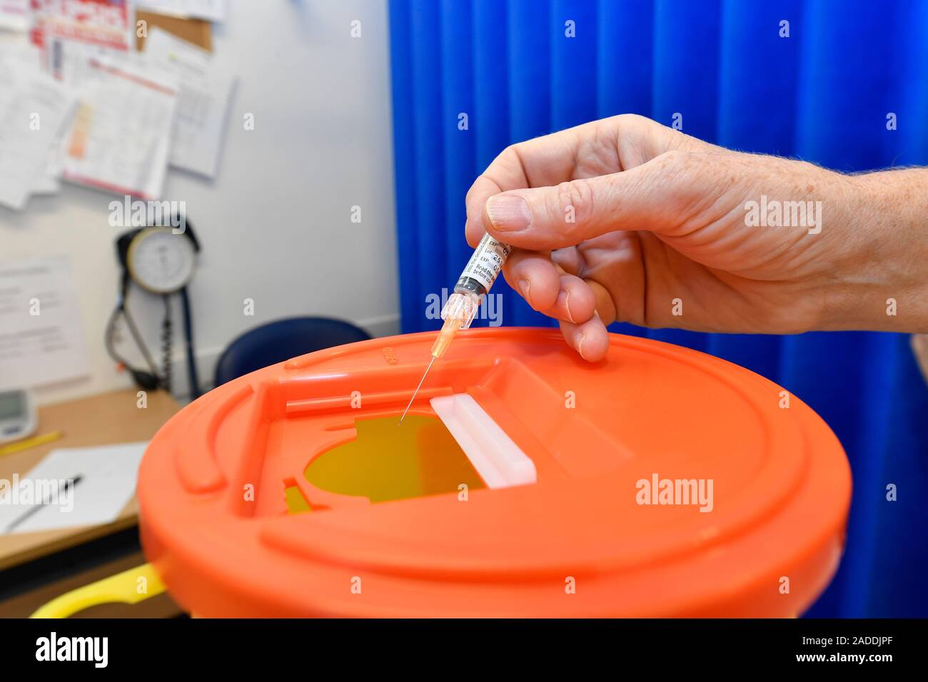 Sharps disposal. Single use syringe being deposited in a sharps bin ...