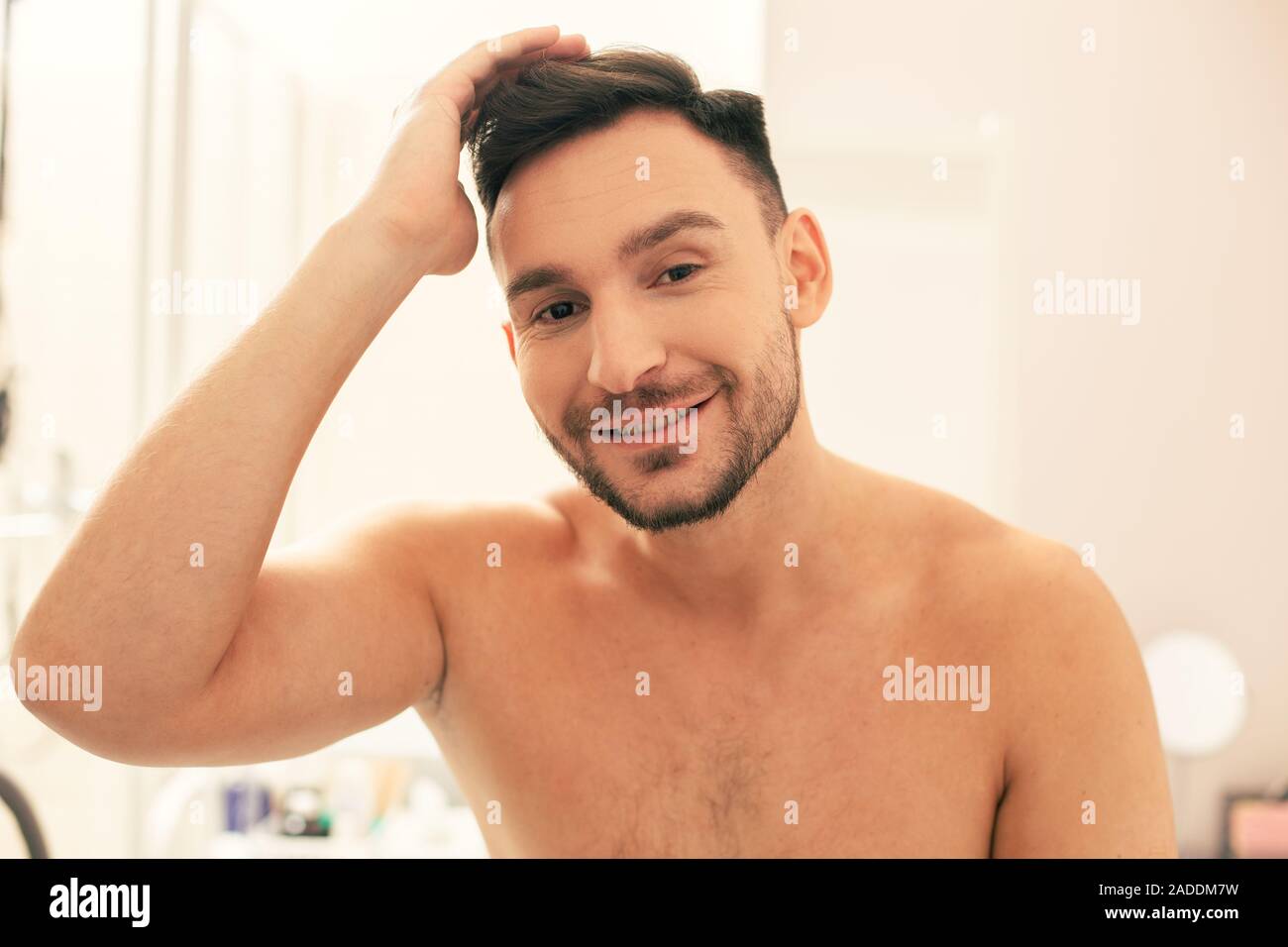 Positive man smiling and putting one hand on his head Stock Photo - Alamy