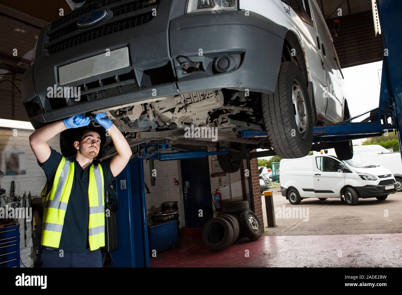 Automotive garage. Mechanic inspecting the underside of a van in a ...