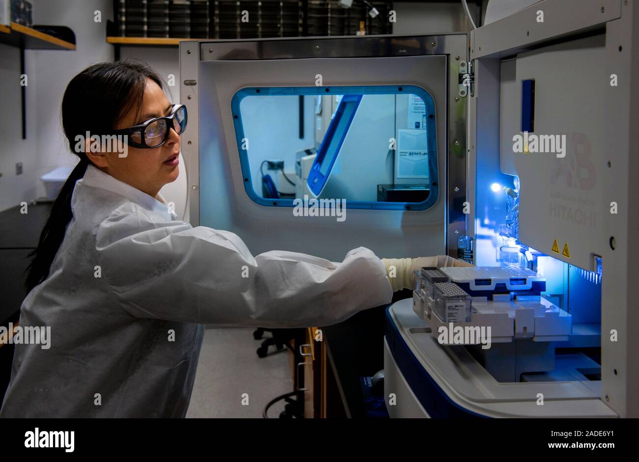 Scientist loading samples into a sequencing machine in a virology ...