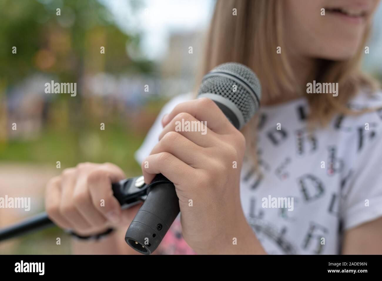 Young girl holding mic with two hands. Microphone and unrecognizable ...