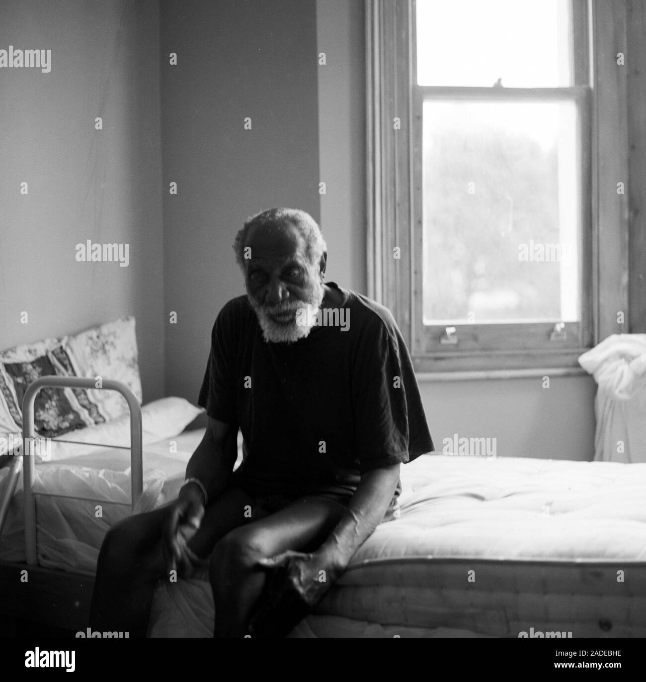 Dementia healthcare. Elderly man with dementia sitting on his bed ...