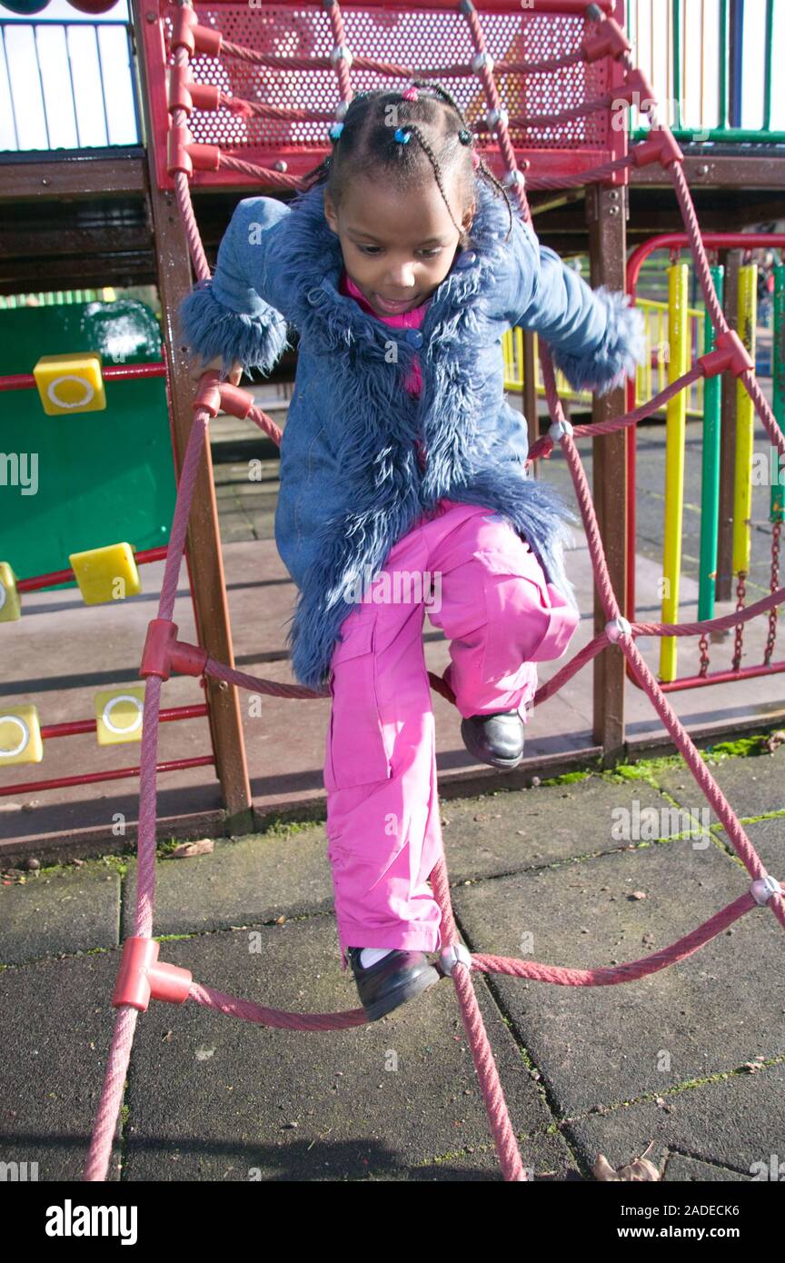 Little girl playing on a climbing frame in the playground Stock Photo ...
